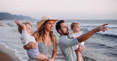 해질녘 여름 휴가에 해변을 걷는 두 명의 유아 자녀를 둔 가족 아들과 딸을 품에 안고 있는 아버지와 어머니 사진 Unsplash의 바닷가 이미지