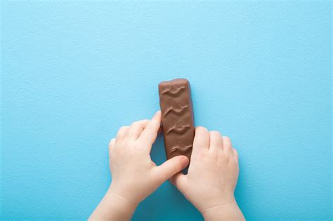 밝은 파란색 테이블 배경에 초콜릿 바를 들고 아기 손 파스텔 색상 달콤한 간식 근접 촬영 관점 샷 하향 보기 먹기에 대한 스톡 사진 및 기타 이미지 Istock