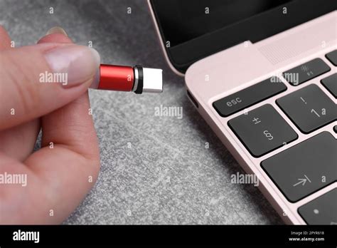 Woman Plugging Usb Cable With Type C Connector Into Laptop Port At Grey Table Closeup Stock