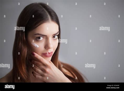 Beautiful Model Applying Cosmetic Cream Treatment On Her Face Stock