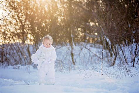 눈 겨울 시간에 테디와 놀고 아기 수제 흰색 스노우 슈트를 입은 어린 유아 소년 일몰에 테디 베어를 들고 겨울 공원에서 야외 에서 놀기 겨울에 대한 스톡 사진 및 기타