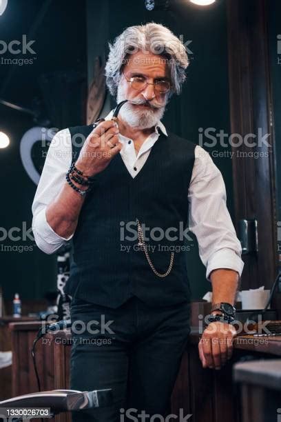 이발소에서 서서 담배를 피우는 회색 머리와 수염을 가진 세련된 현대 노인은 실내에 45 49세에 대한 스톡 사진 및 기타 이미지 45 49세 고풍스런 그루터기 얼굴