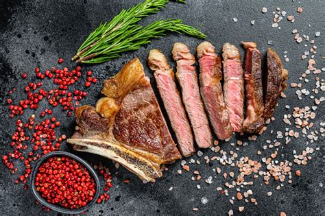 허브와 향신료를 곁들인 구운 카우보이 또는 리비아이 소고기 스테이크 검은 색 배경 위쪽 보기 0명에 대한 스톡 사진 및 기타