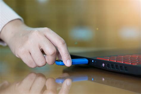 데이터를 복사하거나 전송하기 위해 데스크톱에서 플래시 드라이브를 랩톱 컴퓨터에 연결하는 여성의 손입니다 Usb 메모리에 대한