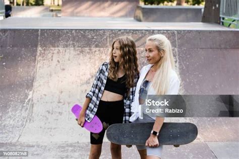 트레이너는 어린이 소녀에게 스케이트 또는 페니 보드를 타도록 교육합니다 스케이트 파크에서 함께 훈련하십시오 극단적 인 라이프