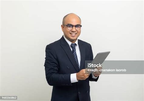 격리된 흰색 배경에 디지털 태블릿을 사용하는 젊은 아시아 사업가의 초상화 사무실 유니폼을 입고 태블릿 컴퓨터를 들고 있는 잘생긴