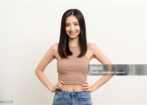 갈색 셔츠를 입은 25세 정도의 아름다운 미소 짓는 행복한 젊은 아시아 여성 고립된 흰색 배경에 서 있는 매력적인 여성 여성 흰색 배경으로 자신감을 갖고 카메라를 보고 있는