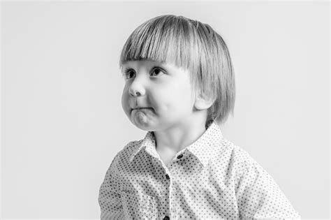 흰색 벽 앞에 서서 미소를 짓고 측면을 바라보는 작은 백인 소년의 초상화를 닫습니다 복사 공간 흑백이있는 작은 어린이 스튜디오 초상화 2 3 살에 대한 스톡 사진 및 기타