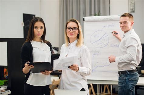 Two Beautiful Office Workers Having Conversation While Man Colleague Drawing Business Strategy