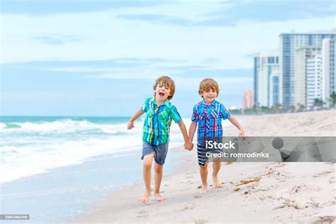 행복 두 작은 바다의 해변에서 실행 하는 남자 아이 재미 있은 귀여운 어린이 형제와 휴가 고 폭풍우 바람이 부는 날에 여름을 즐기는 가장 친한 친구 미국 마이애미의 해변에