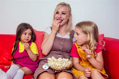 빨간 소파에서 팝콘으로 만화를보고있는 행복한 두 딸과 어머니의 초상화 3 명에 대한 스톡 사진 및 기타 이미지 3 명 30 34세 4 5세 Istock