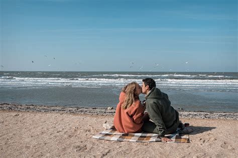 남자와 소녀는 푸른 바다를 배경으로 해변에서 사랑으로 서로를 껴안고 바라 봅니다 남편과 아내의 부드러운 관계 발렌타인 데이에 젊은 부부의 데이트 2명에 대한 스톡 사진 및