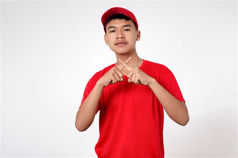 택배 배달 노동자 배송 개념입니다 흰색 배경에 고립된 빨간 유니폼을 입은 젊은 아시아 배달원은 부정적이고 진지한 표정으로 노래를 멈춥니다 18 19세에 대한 스톡 사진 및