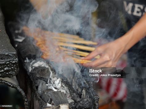 전통적인 숯불에 치킨 사테이 연기와 식욕을 돋우는 표정으로 불에 타서 그릴에 사테이를 요리하는 손 거리에 대한 스톡 사진 및