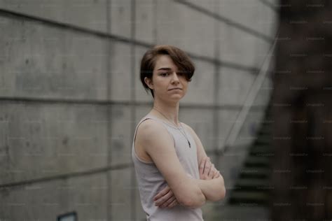 팔짱을 끼고 벽 앞에 서 있는 여자 사진 Unsplash의 트랜스 이미지