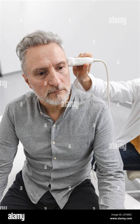 Vascular Scientist Using Ultrasound Scanning Machine For Examining Vessels Of Head Of Senior Man