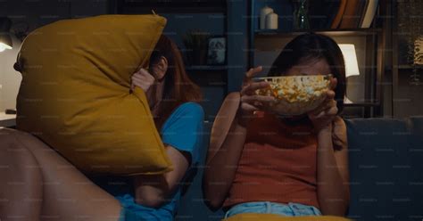 매력적인 아시아 커플 숙녀들은 충격과 두려움의 순간을 느끼고 팝콘을 먹고 집 어두운 밤에 거실의 소파에서 공포 온라인 영화 엔터테인먼트를 봅니다 사진 Unsplash의