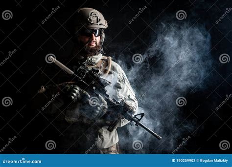 Portrait Of A Soldier In A Military Uniform With A Weapon On A Dark Black Background A Commando