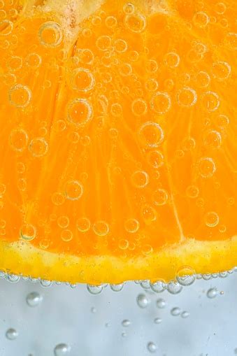 하얀 배경에 잘 익은 오렌지 과일 조각 거품이 있는 액체에 오렌지 과일의 클로즈업 탄산수에 잘 익은 오렌지 과일 조각 탄산수에 담긴 과일의 매크로 이미지 물이 튀는에 대한