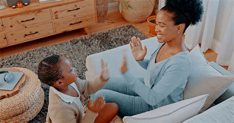 흑인 가족 엄마 소녀는 소파에 손을 얹고 좋은 시간을 보내고 거실에서 유대감을 형성하고 휴식을 취합니다 사랑 행복 엄마와 딸은 소파에서 게임을 하고 박수를 치며 주말을