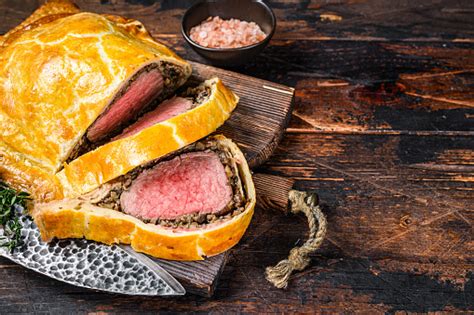 도마에 부드러운 고기와 홈메이드 쇠고기 웰링턴 퍼프 파이 어두운 나무 배경 맨 위 보기입니다 복사 공간 Celebrity Roast에 대한 스톡 사진 및 기타 이미지