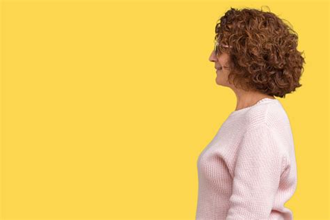 분홍색 스웨터와 선글라스를 착용 한 아름 다운 미들 거 대 수석 여성은 옆을 바라보 며 자신감 있는 미소로 자연 스러운 얼굴로 프로필 포즈를 취하십시오 옆모습에 대한 스톡