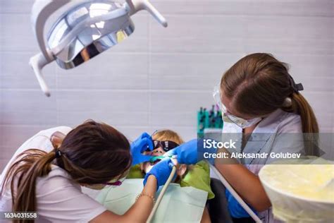 치과 진료실에서 치아 치료를 하는 조수와 함께 치과의사 귀여운 꼬마 소녀 치과 의사 진료소에서 치아를 치료하는 어린 소녀 어린이 의학 치과의 개념입니다 광고문안 공간 복사