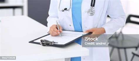 직장에서 알 수 없는 의사 여자 손 클로즈업 진료소 또는 응급 병원에서 리셉션 데스크 근처에 서 있는 동안 여성 의사는 의료 양식을 작성 의학 및 의료 개념 간호사에 대한
