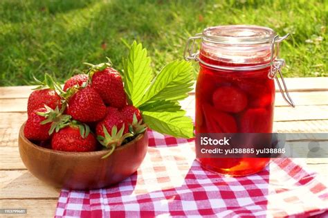 녹색 채소 배경에 빨간색 체크 무늬 냅킨이 있는 나무 테이블에 유리 항아리와 신선한 딸기에 딸기 잼 홈메이드 잼 서머 베리 잼 딸기 통조림 헬 시 채식 0명에 대한 스톡