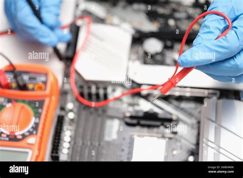 Technician Using Voltmeter To Measure Voltage On Computer Motherboard
