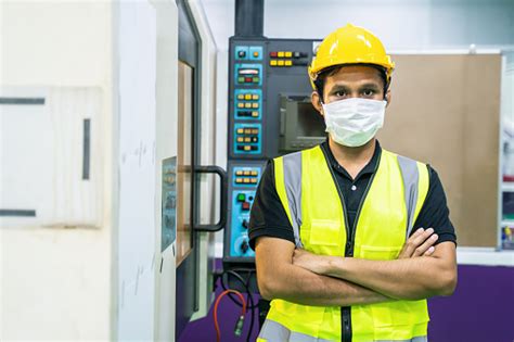 아시아 남성 노동자 는 공장의 생산 라인에서 보호 안전 헬멧과 안경을 착용 자신감과 미소 얼굴로 산업 공장에서 첨단 기술 기계에서 운영하는 남자 기계류에 대한 스톡 사진 및