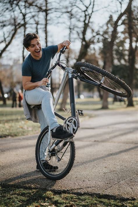 Joyful Man Doing A Wheelie With His Bicycle In The Park On A Sunny Day Stock Image Image Of