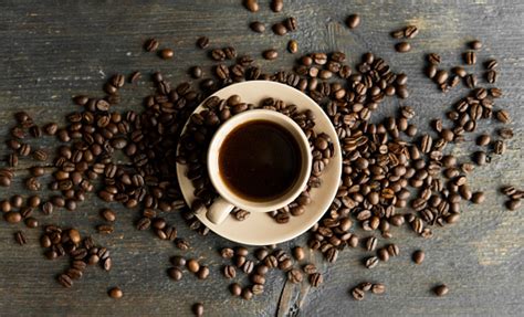 나무 테이블 배경에 구운 커피 콩커피 컵 나무 테이블에 흩어져 있는 커피 콩이 있는 검은 색 코프 잔 신선한 커피 콩 갈색에 대한 스톡 사진 및 기타 이미지 Istock