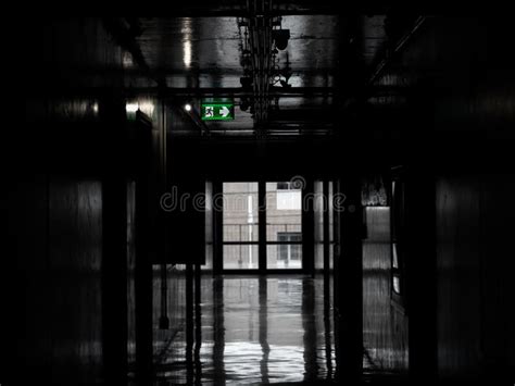 Green Exit Fire Sign Hanging On Ceiling On Dark Mysterious Corridor In