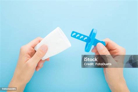 젊은 여자는 막대기에 집에서 만든 얼음 아이스 캔디를 담을 수 있는 하얀 플라스틱 용기를 들고 있다 하늘색 테이블 배경입니다 파스텔 색상 근접 촬영 차갑고 달콤한 스낵 시점