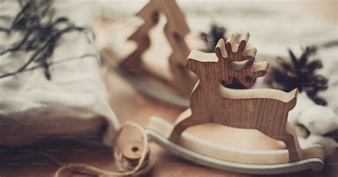 소박한 순록 크리스마스 장난감은 조명 나무 나무 꼬기 녹색 가지가 있는 린넨 선물 솔방울을 배경으로 나무 테이블에 있습니다 즐거운 성탄절 텍스트를 위한 공간입니다