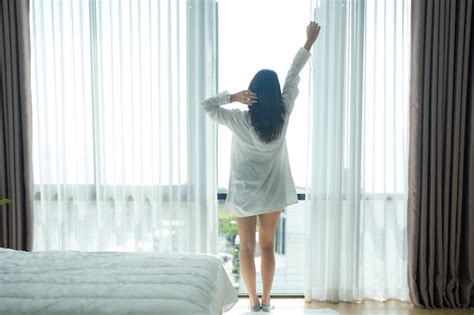 Premium Photo Asian Woman Standing By The Window And Stretching In The Morning