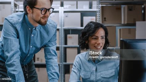 남성과 여성의 창 고 재고 관리자 이야기 문제 해결 개인용 컴퓨터를 사용 하 여 및 재고를 확인 합니다 진열대의 배경 행에서 골 판지 상자 패키지의 전체 2명에 대한 스톡