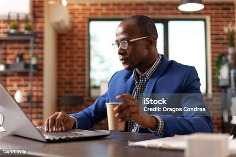 노트북으로 비즈니스 프로젝트를 진행하고 커피 한 잔을 들고 있는 아프리카계 미국인 경영자에 대한 스톡 사진 및 기타 이미지 경영자 기업가 남자 사업가 Istock