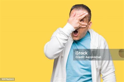 중세 아랍 사람 얼굴과 손으로 눈을 덮고 충격에서 격리 된 배경 엿보기에 셔츠를 입고 당황된 표정으로 손가락을 통해 찾고 가리기에 대한 스톡 사진 및 기타 이미지 Istock