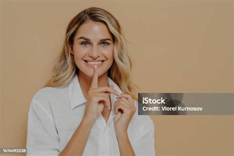 젊은 아름다운 긍정적 인 여성 금발 염색 머리 터치 입술 와 손가락과 미소 에 카메라 손가락을 입술에 대기에 대한 스톡 사진 및 기타 이미지 손가락을 입술에 대기