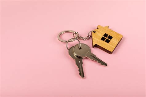 배경에 열쇠 고리가 있는 집 모양의 열쇠 고리 부동산 및 이사 또는 부동산 임대에 대한 개념 부동산 구입 모형 열쇠 고리 집