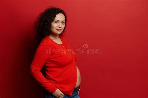 Confident Portrait Of Dark Haired Curly Beautiful Pregnant Woman In Red