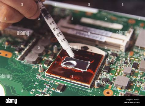 technician applying thermal paste with syringe on the cpu processor on