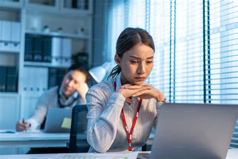 지친 아시아의 아픈 비즈니스 여성 노동자가 사무실에서 테이블에서 일하고 있습니다 바쁜 직원들은 늦은 퇴근으로 피곤하고 두통을 느끼며 밤에 직장에서 컴퓨터 책상에서 작업