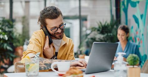 카페에서 휴대폰으로 전화를 걸면서 컴퓨터를 사용하는 젊은 행복한 남자 사진 Unsplash의 사업가 이미지