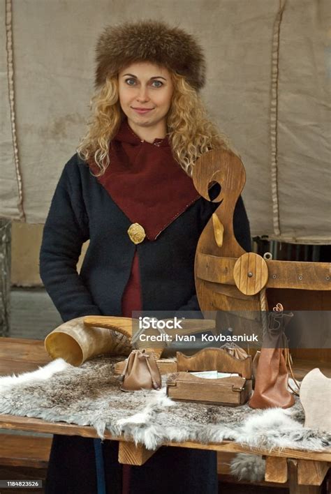 푸른 눈을 가진 소녀는 룬에 경이로움 중세 축제에서 바이킹 의상을 입은 금발 북부 민족의 정통 의류와 라이프 스타일 나무 테이블에 모피 고대의에 대한 스톡 사진 및 기타