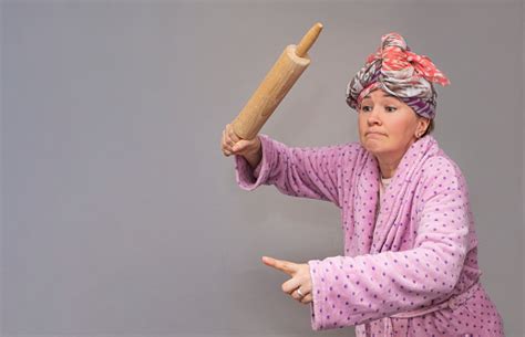 드레싱 가운을 입은 여성과 머리에 스카프를 두르고 있는 한 여성이 손에 달린 핀을 들고 카메라를 진지하게 바라보고 있다 회색 배경에 집 옷을 입고 있는 3040세 여성