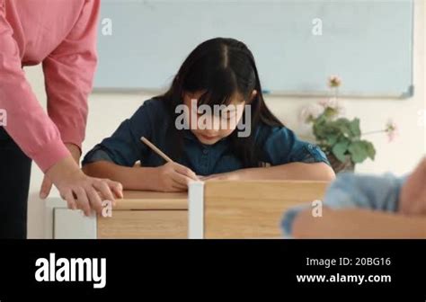 Asian Girl Writing Or Taking A Note While Teacher Checking Classwork