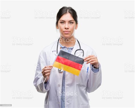 스마트 얼굴 심각한 생각에 자신감 표현으로 독일의 국기를 들고 젊은 히스패닉 의사 여자 감정에 대한 스톡 사진 및 기타 이미지 감정 건강관리와 의술 기 Istock